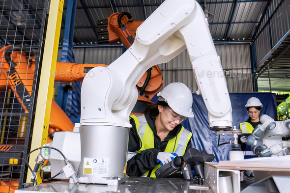 Young female asian service engineer holding robot controller operate ...