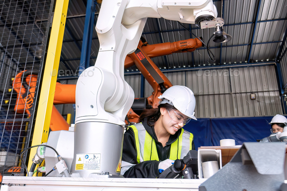 Young female asian service engineer holding robot controller operate ...