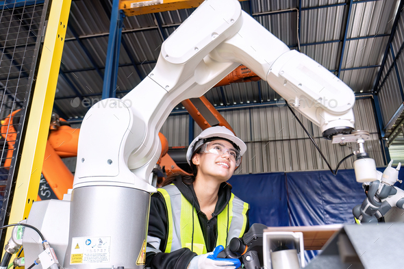 Young female asian service engineer holding robot controller operate ...