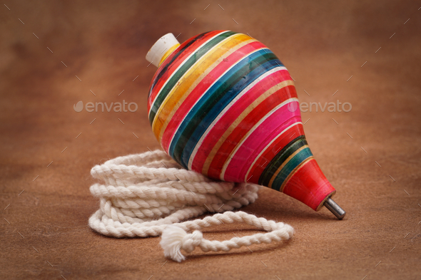 Colorful trompo on a brown background Stock Photo by wirestock | PhotoDune