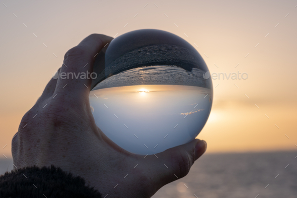 Closeup of a man holding a glass sphere in front of the beautiful calm ...