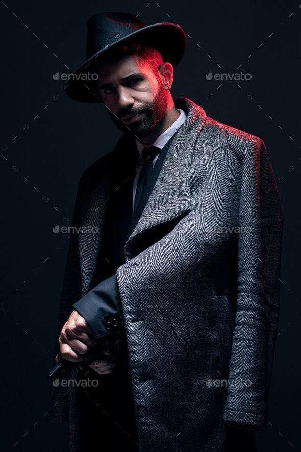 Gangster, portrait and holding gun on studio background in dark secret ...