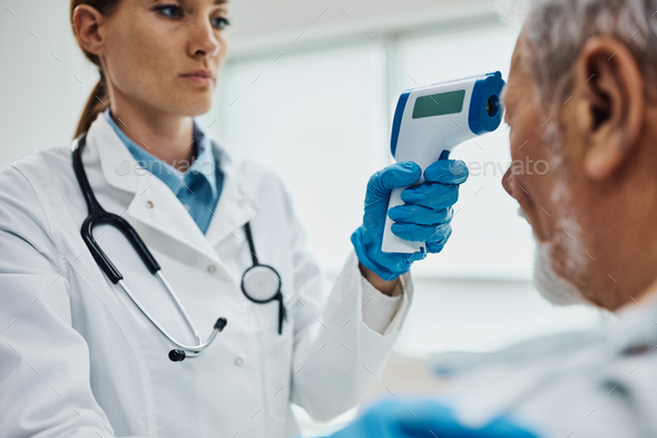 Close up of doctor using infrared thermometer while measuring ...