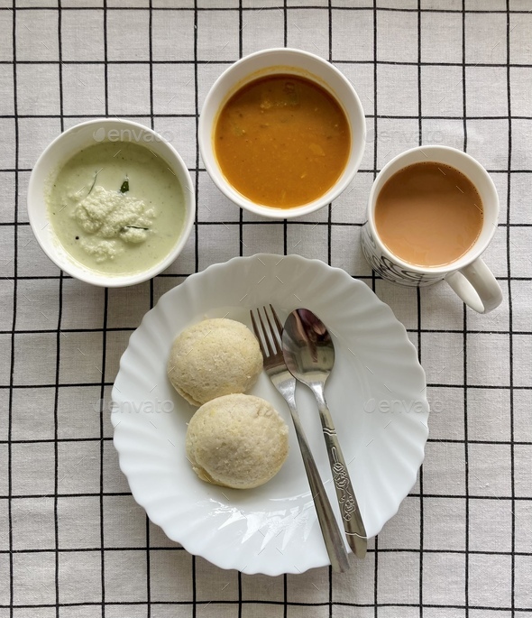Top view of a serving of idly with sambar, coconut chutney and tea ...