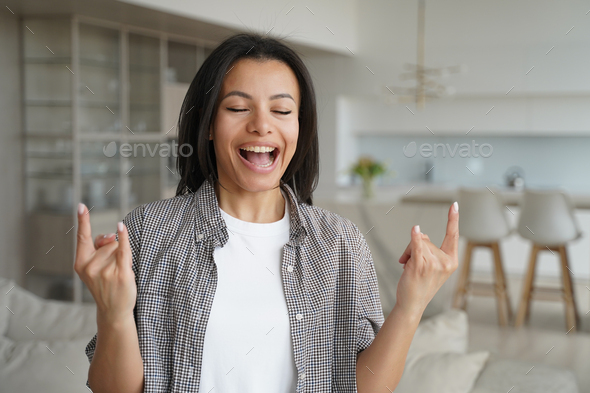 Excited cool young woman shows hard rock hand gesture, screaming ...