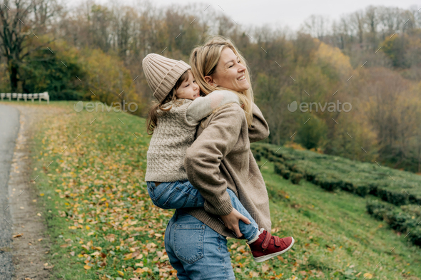 Little Girl Riding On Her Mother's Back Stock Photo by titovailona