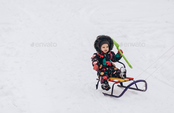 Little girl sledging downhill an having fun. Pink sledge and jacket ...