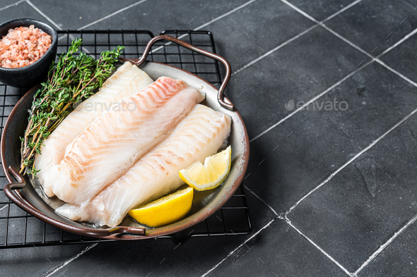 Fresh raw cod fish fillets with herbs served on steel tray. Black ...