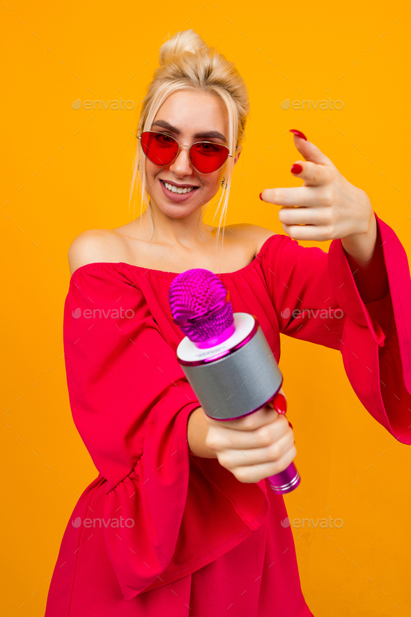 European blond girl singer in a bright red dress with manicure with a ...