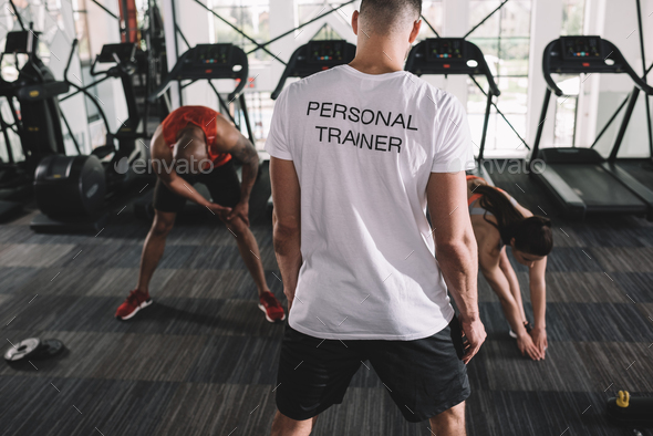 back view of personal trainer supervising multicultural athletes ...