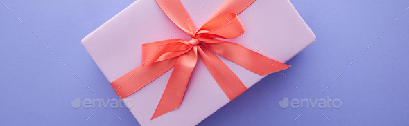 top view of violet gift box with red ribbon and bow on purple ...