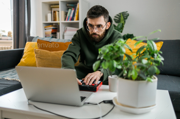 Man music producer or arranger using laptop and midi keyboard and other ...