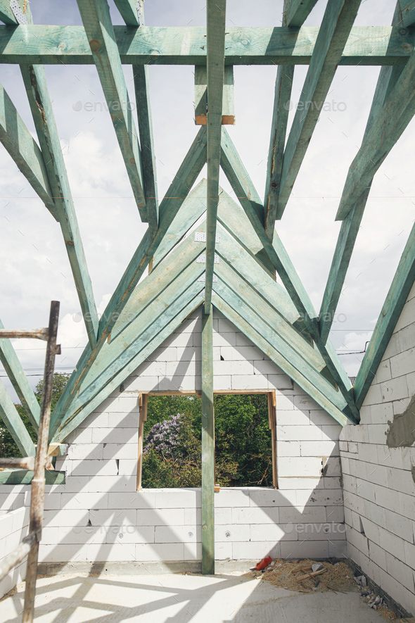 Unfinished roof trusses, view in attic with rafters and beams against ...