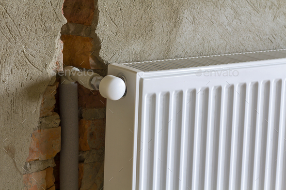 Close-up side view of isolated installed heating radiator on brick ...
