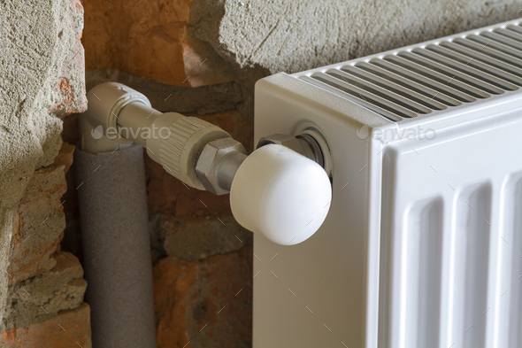 Close-up side view of isolated installed heating radiator on brick ...