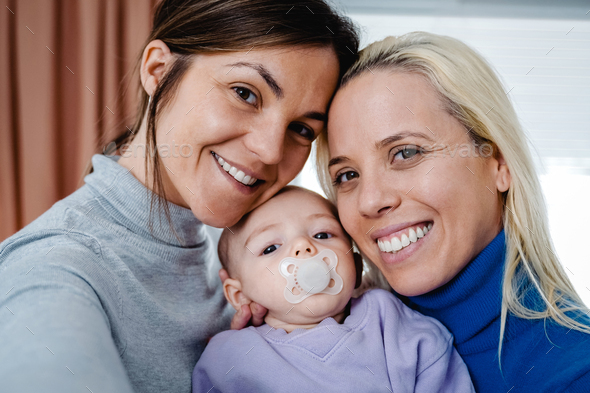 Gay lesbian couple and newborn baby taking selfie picture indoors at ...