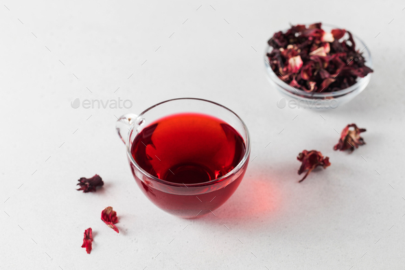 Herbal tea made from hibiscus petals in a transparent cup and a bowl of ...