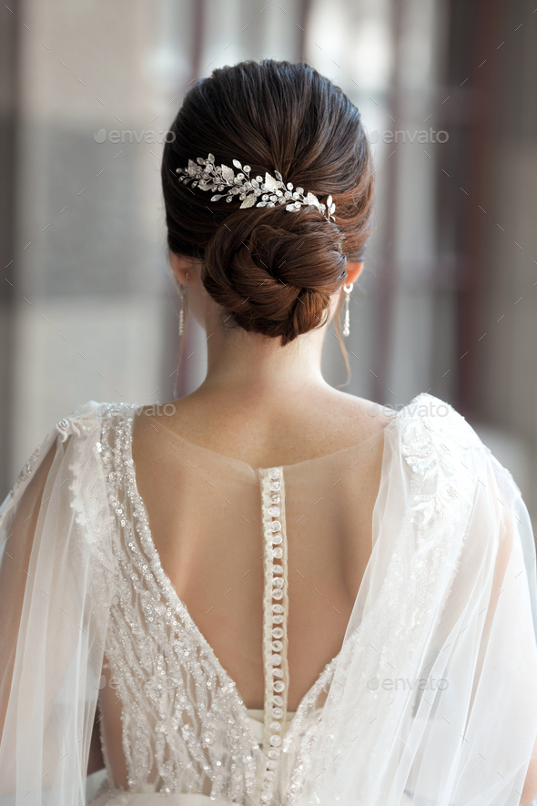 Bride in wedding dress from behind with glam bun hairstyle outdoors ...