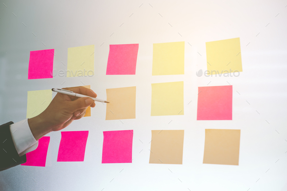 Close up hand businessman writing sticky notes on glass wall in office ...