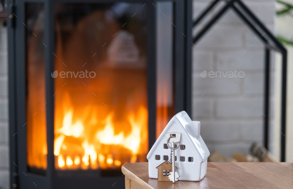 Key to house with keychain against background of fireplace stove with ...