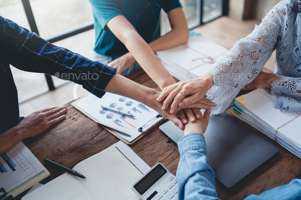 Group of businesspeople putting their hands together to work together on new projects to see ...