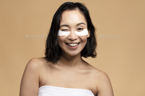 Smiling asian woman with eye patches winking isolated on beige Stock ...