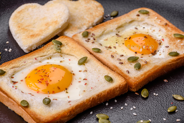 Heart shaped fried egg in bread toast with sesame seeds Stock Photo by chernikovatv