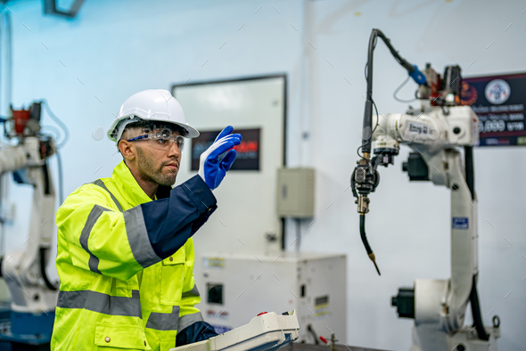 Engineer Man working at industrial robot in factory industrial. robotic ...