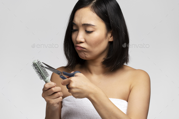 Sad asian woman holding comb and scissors and feeling worry about ...