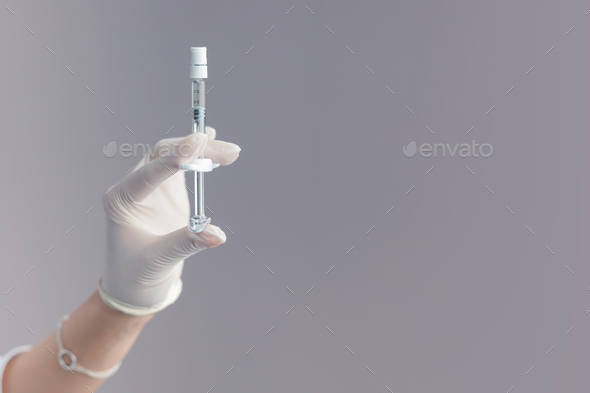 Cosmetologist hand in medical glove holds syringe for injection with ...