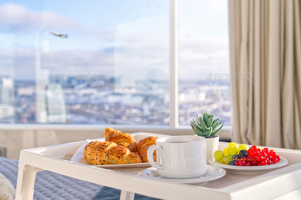 White Tray with tasty breakfast on bed in light bedroom with big ...