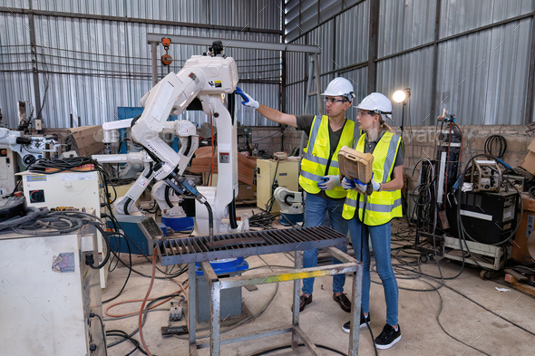 In robotic training center instructor teaching girl engineer how to operate and program robot ...