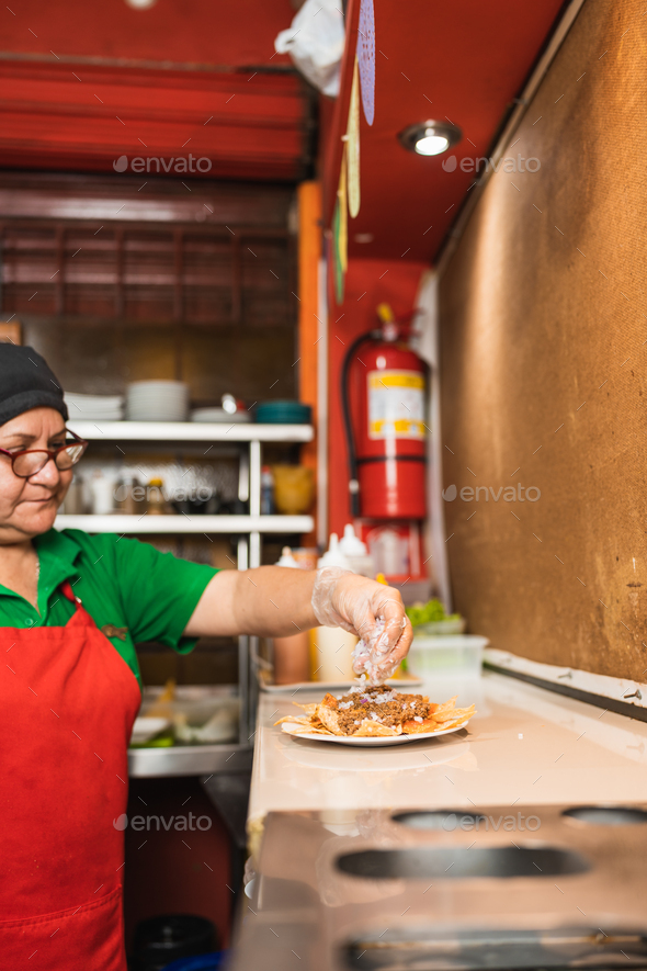 Cook adding cheese to a dish of nachos in a restaurant Stock Photo by ...