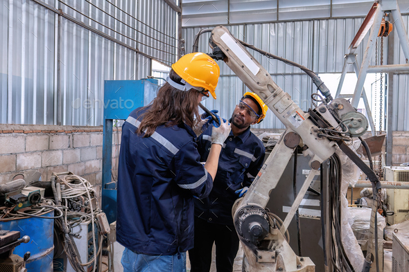 Factory maintenance engineer working with old defected robotic arm in ...