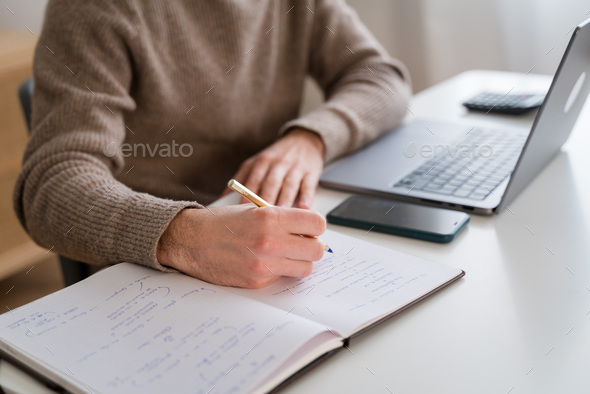 Crop man writing in notepad while working on project Stock Photo by ...