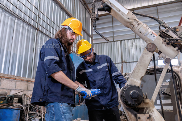 Factory maintenance engineer working with old defected robotic arm in ...