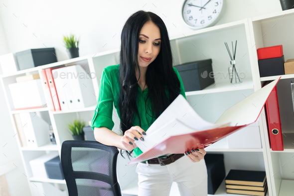 A young girl in the office is holding a folder with documents. Stock ...