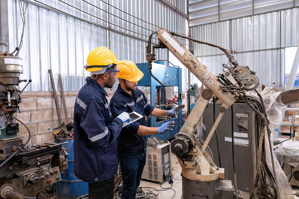 Factory maintenance engineer working with old defected robotic arm in ...