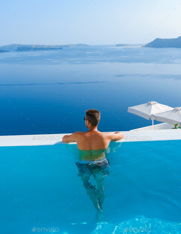 man relaxing in swimming pool during vacation at Santorini infinity ...
