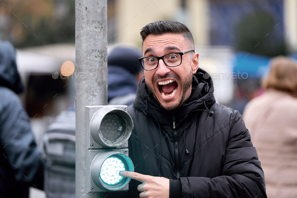 Man pointing to the green light of the traffic light on the street ...