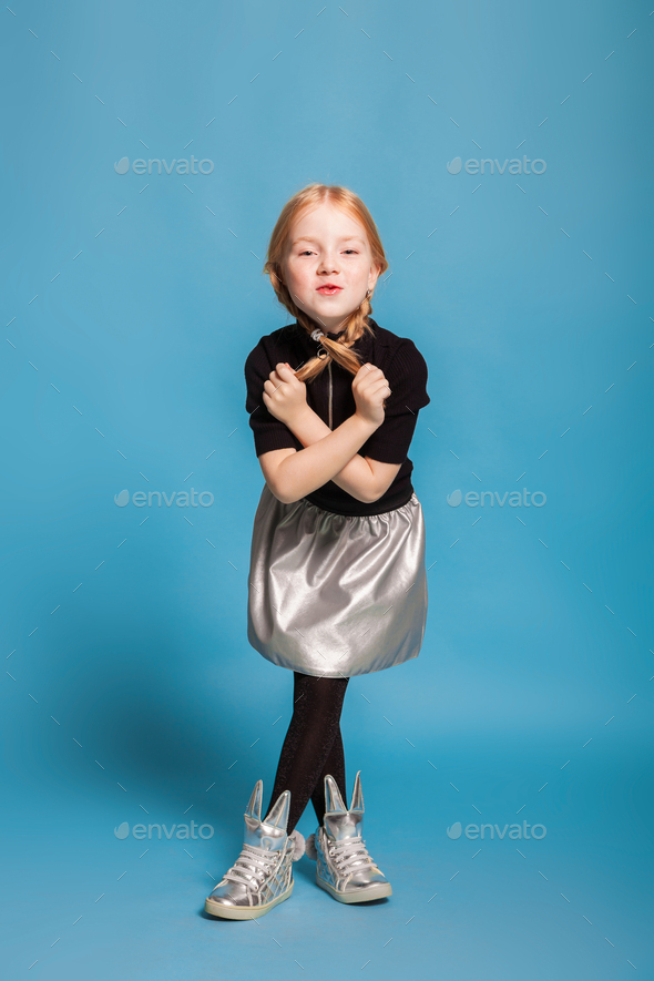 little girl with braids in stylish clothes on blue background Stock ...