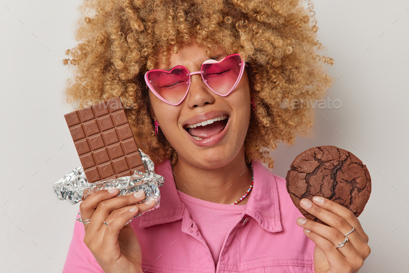Upset crying curly haired woman has addiction to sugary food holds bar ...