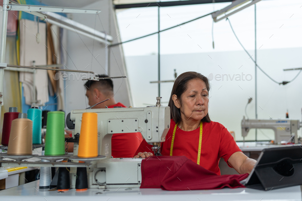 People sewing in a workshop using machines and a digital tablet Stock ...