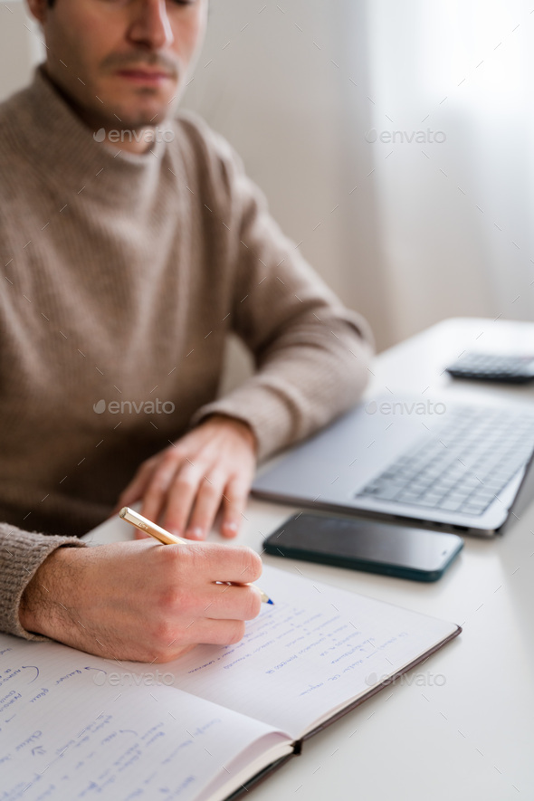Crop man writing in notepad while working on project Stock Photo by ...