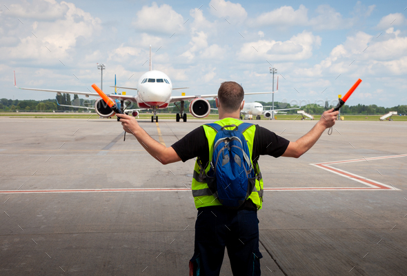 Aviation marshaller meets airplane at the airport. Airport worker ...