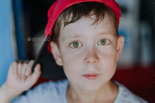close-up portrait of a big-eyed boy in a cap with green eyes, like a ...