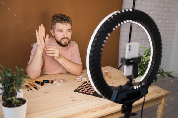 Famous blogger. Cheerful male vlogger showing cosmetics products while ...