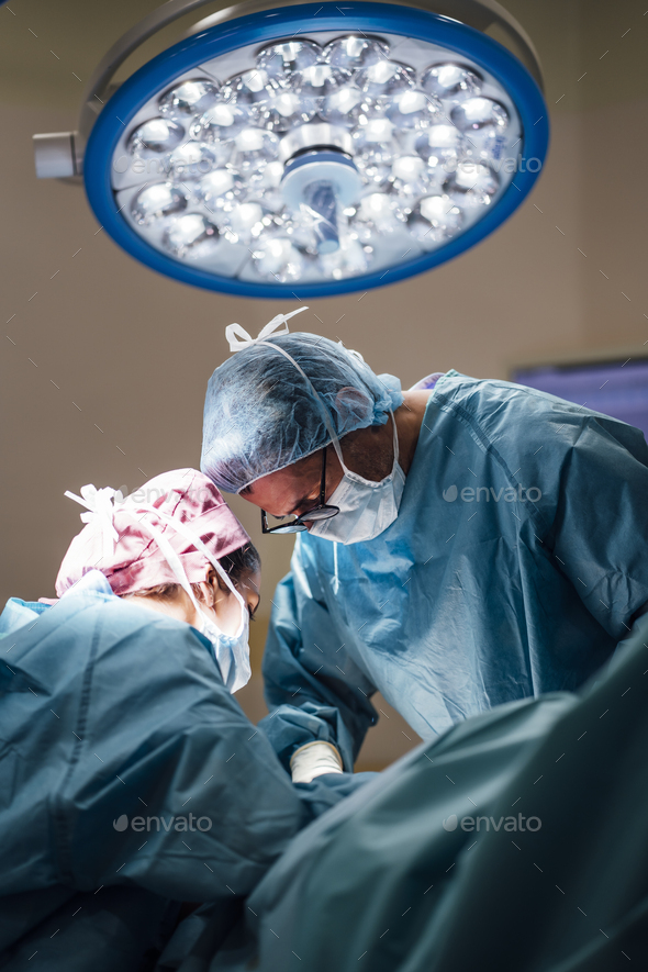 Surgeons and nurse during a foot surgery Stock Photo by carrascosaoscar