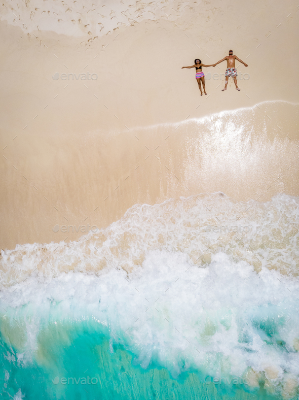 Drone view from above at a tropical beach with men and woman laying ...