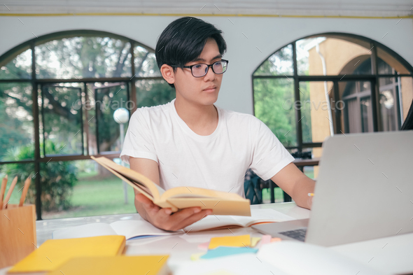 Young Asian male student is preparing to reading a books for exams at ...